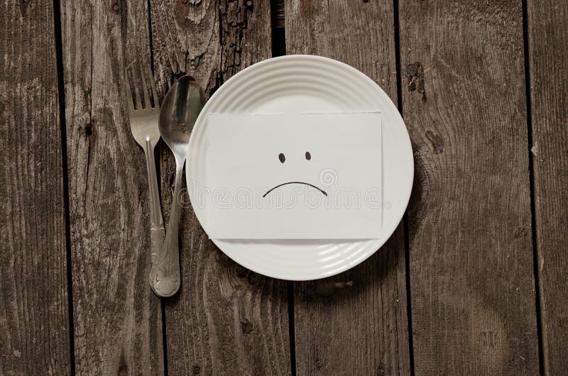 An Empty Plate with a Sad Smiley on Paper and a Fork with a Spoon on a ...