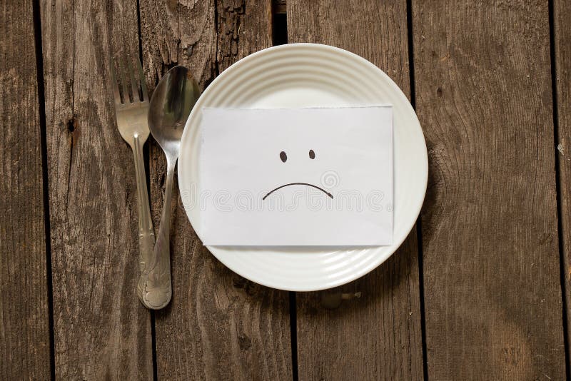 An Empty Plate with a Sad Smiley on Paper and a Fork with a Spoon on a ...