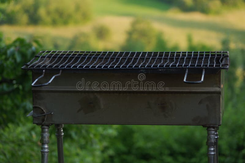 Empty Portable BBQ Grill in Front of a Fresh Green Summer Landscape ...