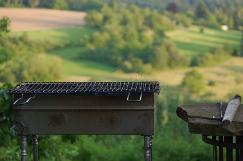 Empty Portable BBQ Grill in Front of a Fresh Green Summer Landscape ...