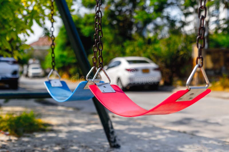 Empty Red and Blue Swings in a Sunny Park Playground Setting Stock ...