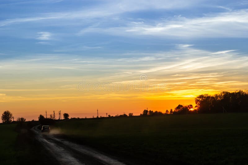 An Empty Road Going Forward between a Green and Plowed Field with Trees ...