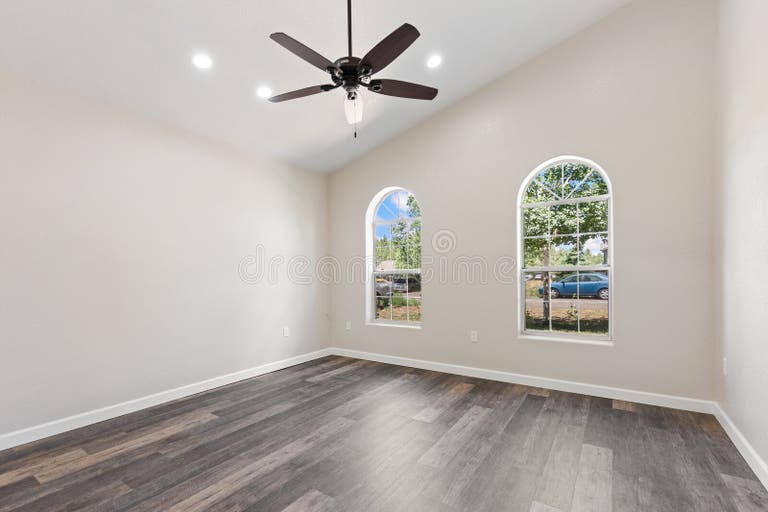 An Empty Room Featuring a Ceiling Fan and Two Windows Allowing Light in ...