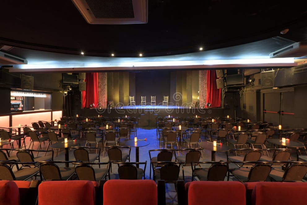 An Empty Theater with Stalls with Tables and a Stage with Four Chairs ...