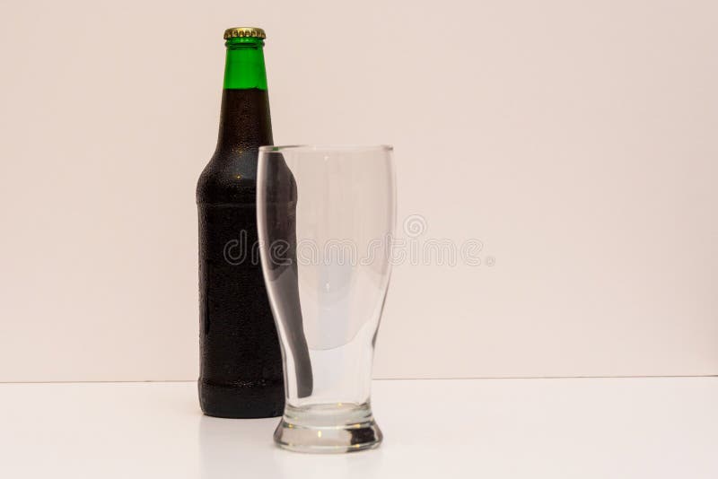 Empty Transparent Glass and a Closed Green Bottle with Dark Beer on a ...