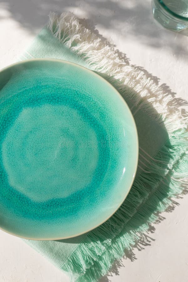 Empty Turquoise Ceramic Plate with Napkin with Fringe on White Plaster ...