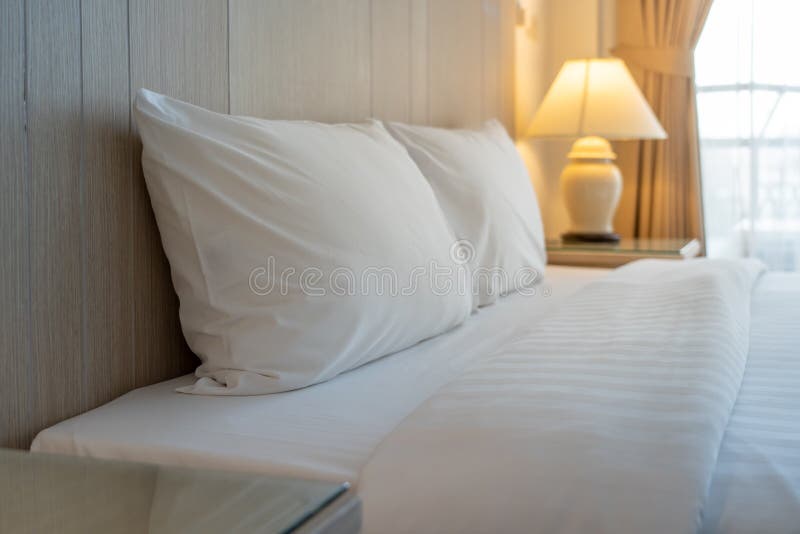 An Empty White Bed with White Pillows and Table Lamp in a Clean Bedroom ...