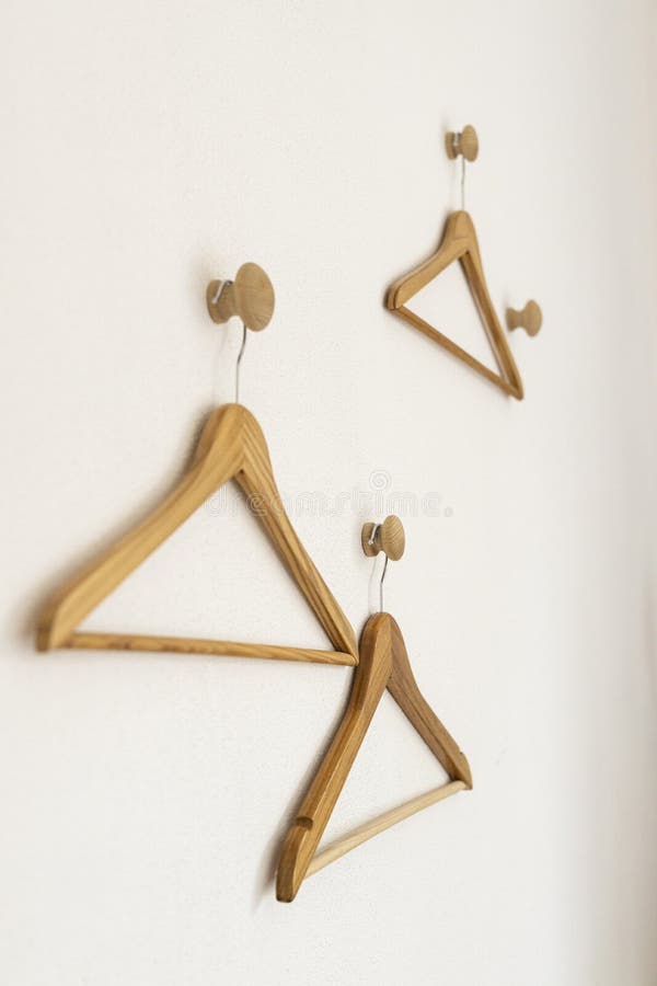 Three Hangers Hanging on Hooks on a White Wall Stock Image - Image of ...