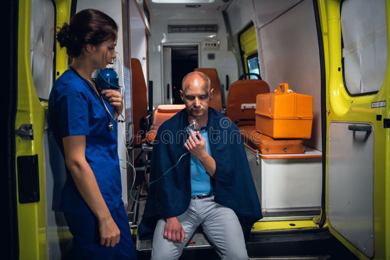 An EMT Talking To Her Patient, Who is Sitting in an Ambulance Stock ...