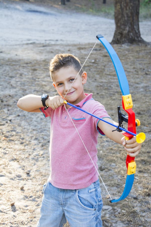 En El Verano En El Bosque El Muchacho Tira Una Flecha Imagen de archivo ...