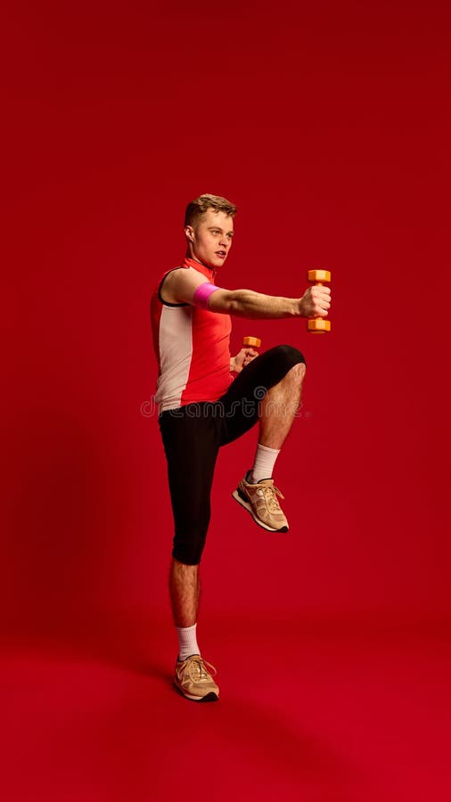 Energetic Man Doing Dynamic Punch and Knee Lift while Holding Dumbbells ...