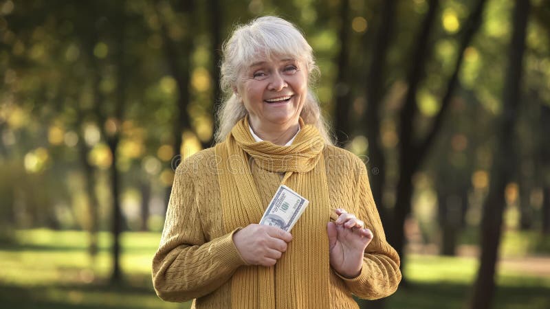 Energetic Old Lady Holding Stack of Dollar Bills in Park, Planned ...