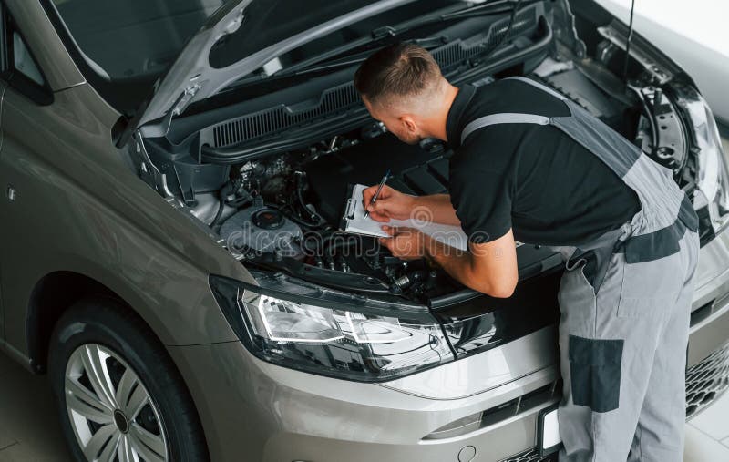 Engine Repair. Man in Uniform is Working in the Autosalon at Daytime ...