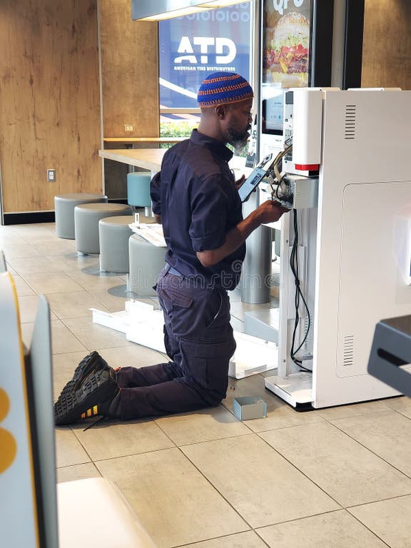 An Engineer Adjusts a New Customer Service Machine Using a Tablet at a ...