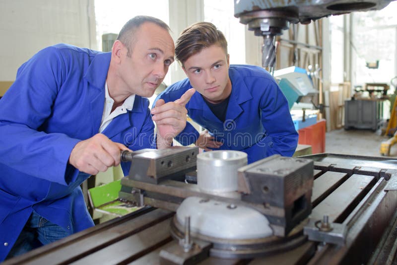Engineer with Apprentice Pointing To Machine Stock Image - Image of ...