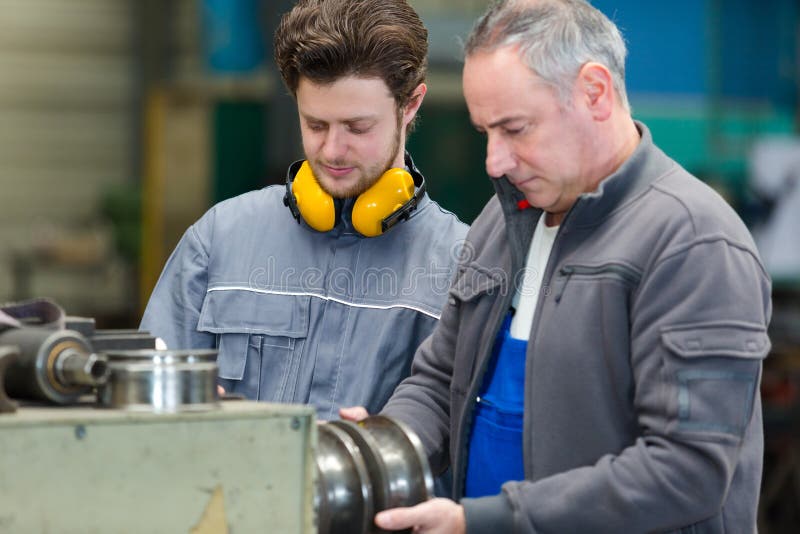 Engineer and Apprentice Using Machinery in Factory Stock Photo - Image ...