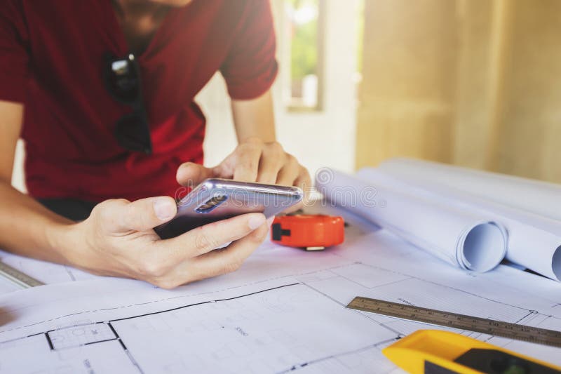 Engineer or Architect Using Cell Phone on Blueprint in Building ...