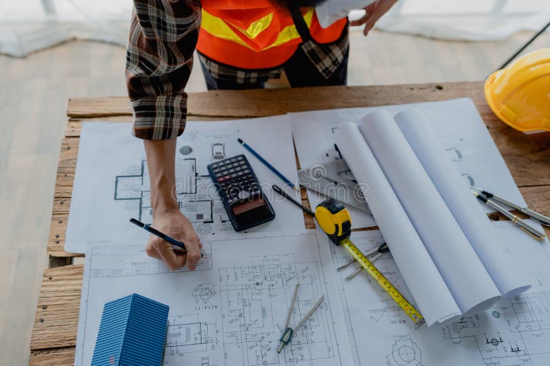 Engineer Brainstorming and Measuring for Cost Estimating on Blueprint ...