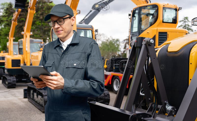 Engineer with a Digital Tablet Stands Next To Construction Excavators ...