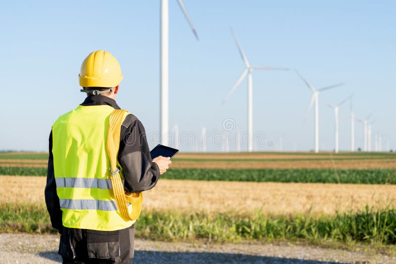 Engineer with Digital Tablet Works on a Field of Wind Turbines Stock ...