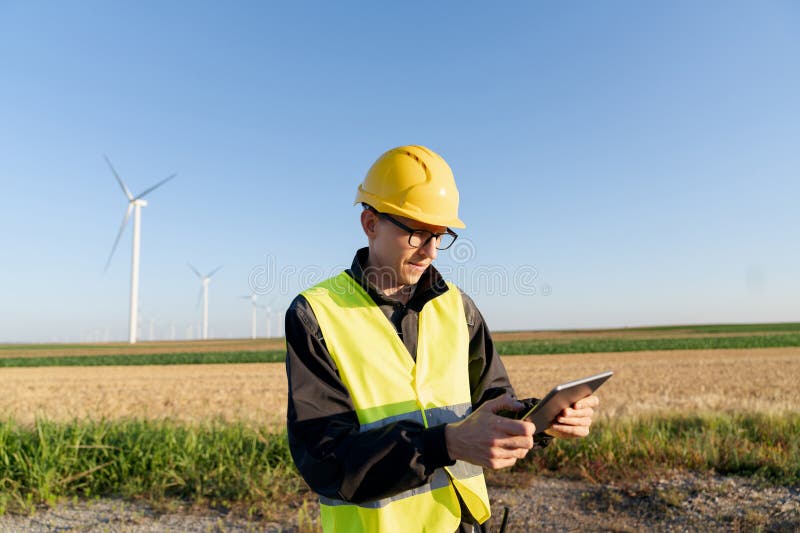 Engineer with Digital Tablet Works on a Field of Wind Turbines Stock ...