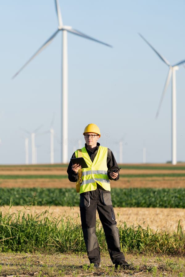 Engineer with Digital Tablet Works on a Field of Wind Turbines Stock ...