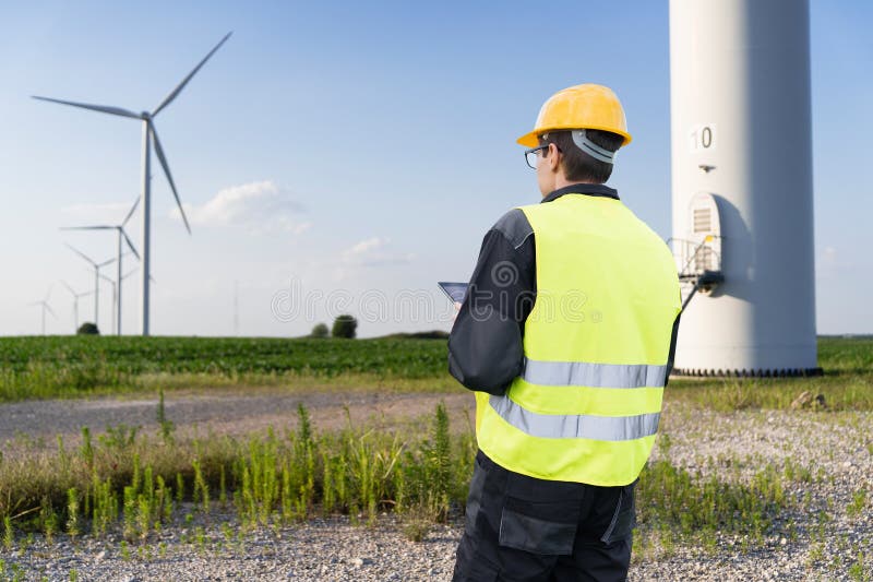 Engineer with Digital Tablet Works on a Field of Wind Turbines Stock ...
