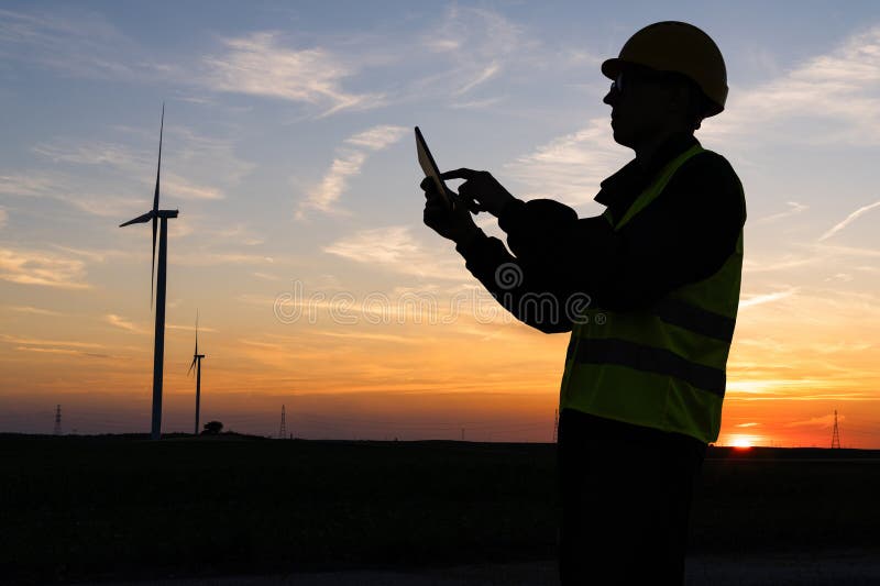 Engineer with Digital Tablet Works on a Field of Wind Turbines at ...