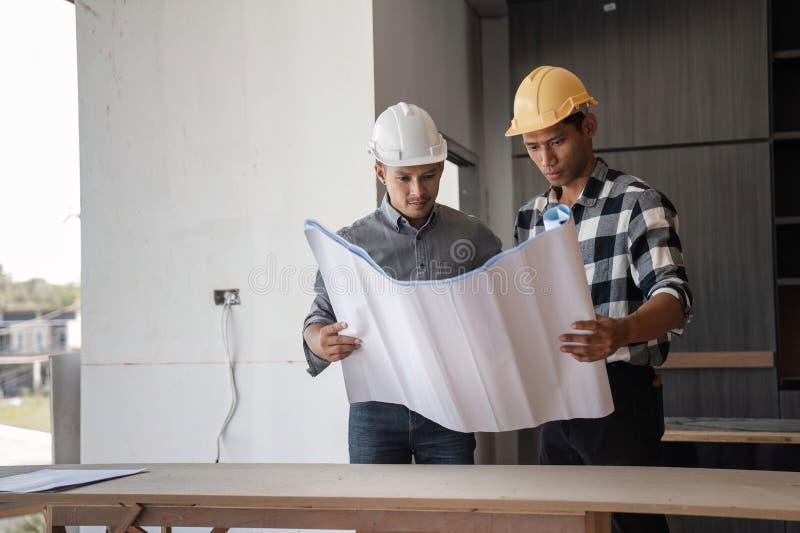 Engineer Discussing and Planning Work while Holding Construction Plan ...