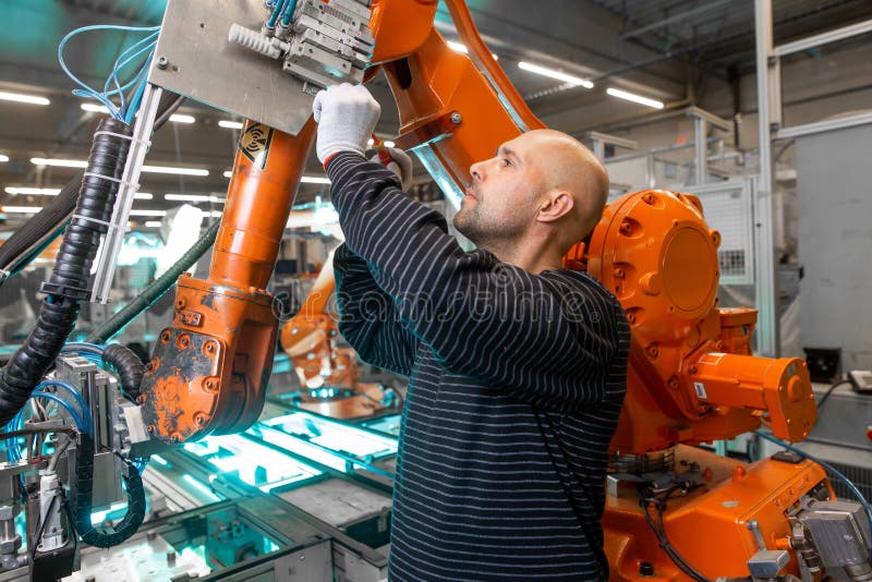 Engineer Doing Maintenance on a Automatic Robot Arms in Automotive ... Engineer Doing Maintenance on a Automatic Robot Arms in Automotive ...