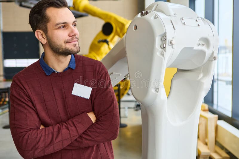 Engineer with Folded Arms Standing Next To Industrial Robot in Modern ... Engineer with Folded Arms Standing Next To Industrial Robot in Modern ...