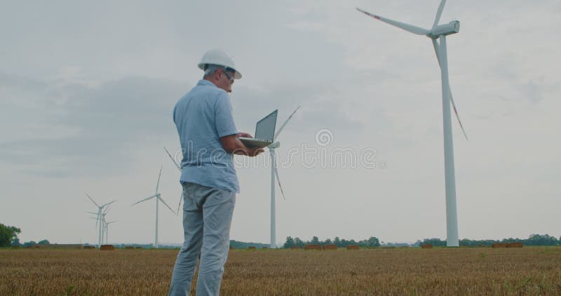 Engineer in Hardhat Uses Laptop Near Wind Turbines Environmental Stock ...