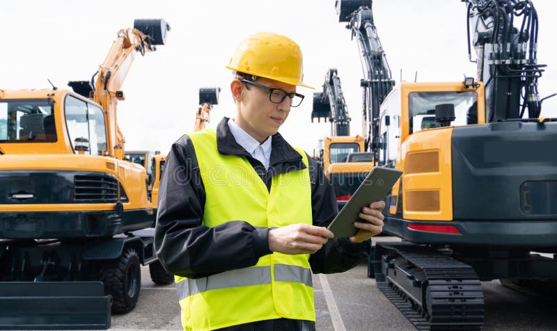 Engineer in a Helmet with a Digital Tablet Stands Next To Construction ...