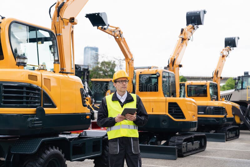 Engineer in a Helmet with a Digital Tablet Stands Next To Construction ...