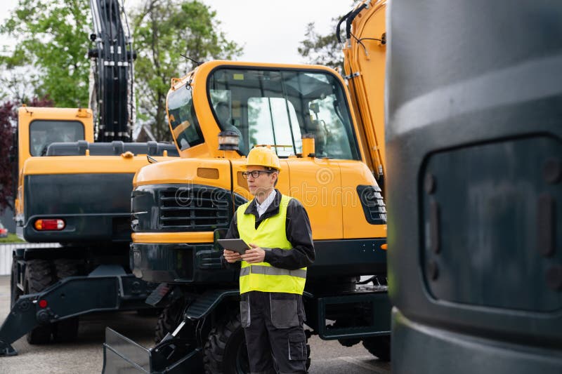 Engineer in a Helmet with a Digital Tablet Stands Next To Construction ...