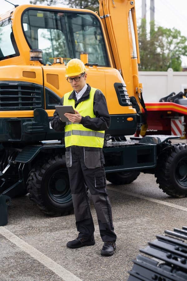 Engineer in a Helmet with a Digital Tablet Stands Next To Construction ...