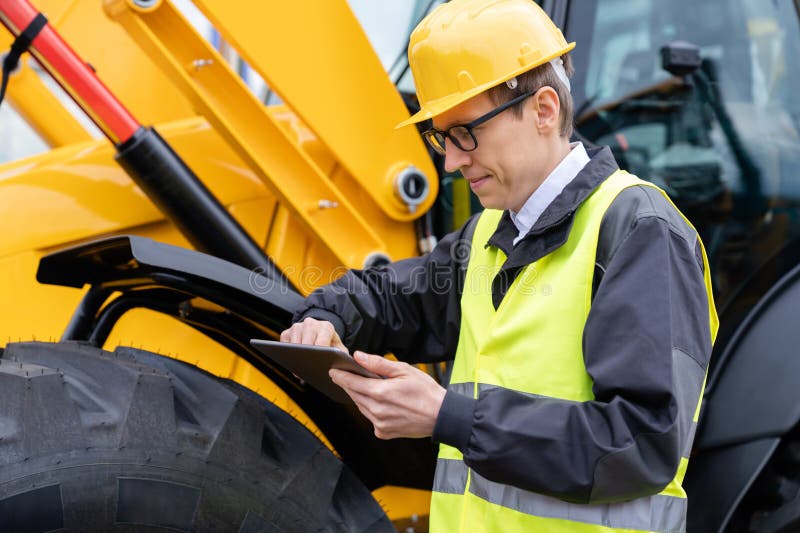 Engineer in a Helmet with a Digital Tablet Stands Next To Construction ...