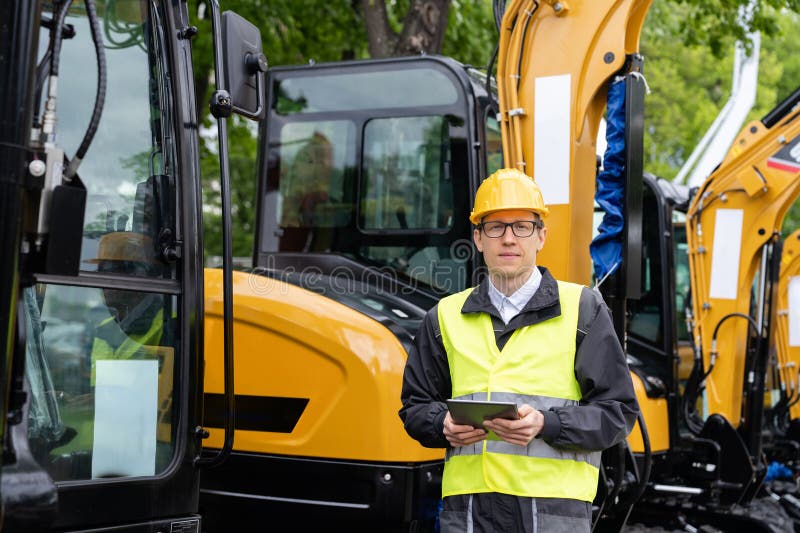 Engineer in a Helmet with a Digital Tablet Stands Next To Construction ...