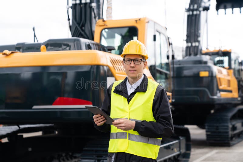 Engineer in a Helmet with a Digital Tablet Stands Next To Construction ...