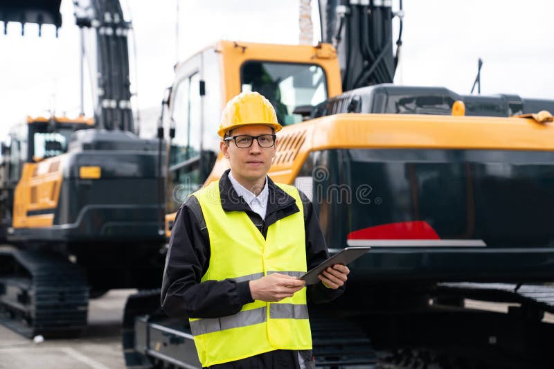 Engineer in a Helmet with a Digital Tablet Stands Next To Excavators ...
