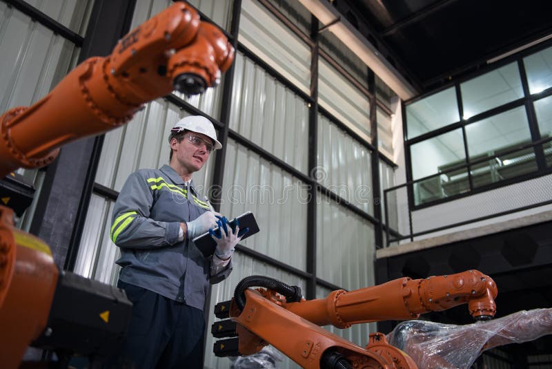 Engineer Standing by Robotic Arm and Operating Machine in Industry ...