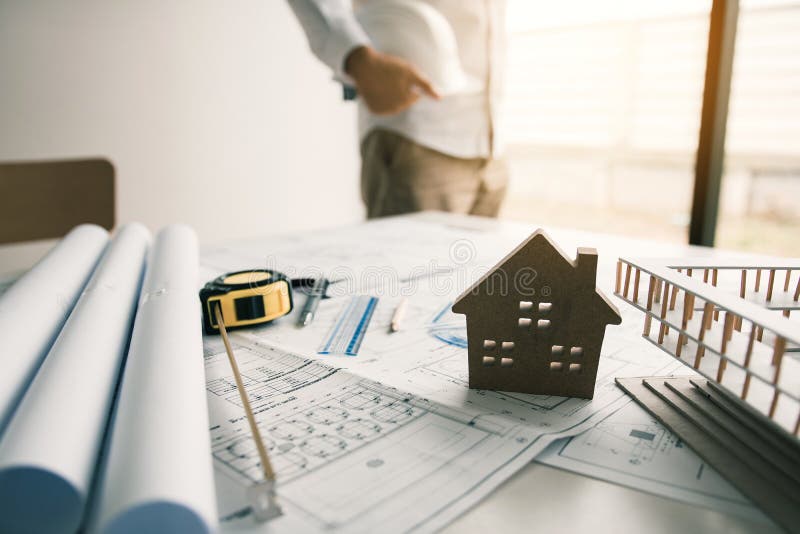 Engineer is Holding a Helmet Standing in His Office and Has a Blueprint ...