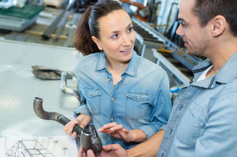 Engineer Holding Metal Component in Discussion with Colleague Stock ...