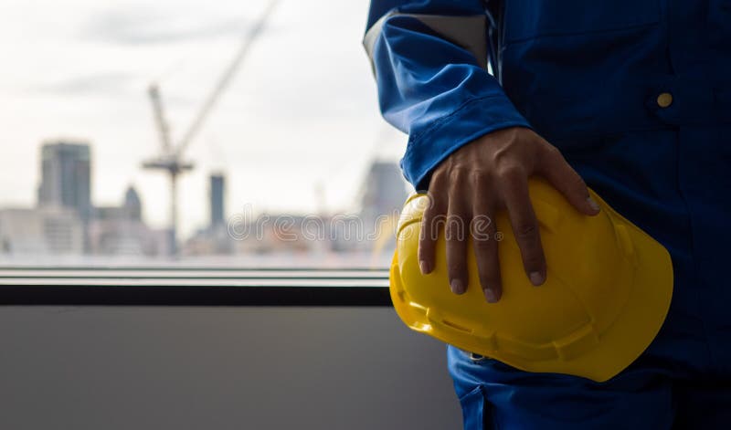 Engineer Holding Yellow Helmet with Construction Building Site ...