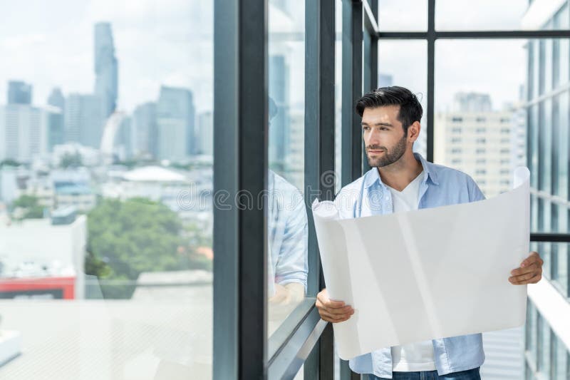 Engineer Looks at Skyscraper and City View while Holding Project Plan ...