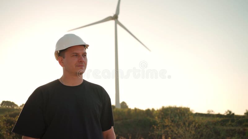 Engineer Man in White Hard Hat Walking on Field with Huge Windmills ...