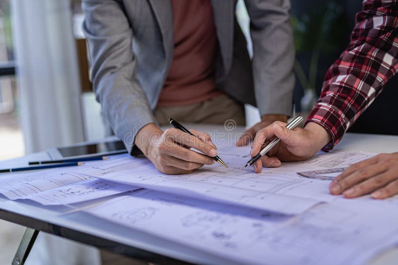 Engineer Pointing at Blueprint and Using Laptop To Draw Building Design ...