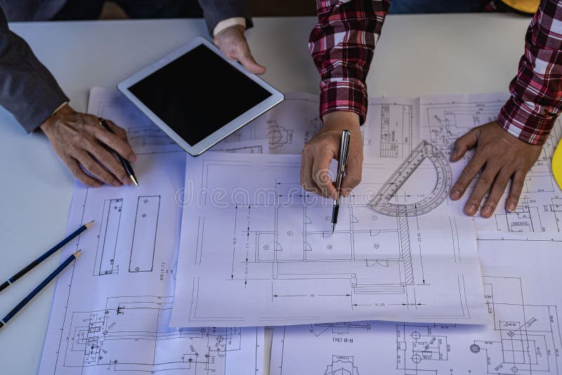 Engineer Pointing at Blueprint and Using Laptop To Draw Building Design ...