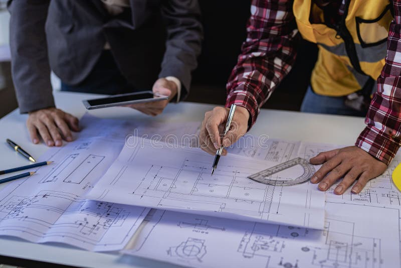 Engineer Pointing at Blueprint and Using Laptop To Draw Building Design ...