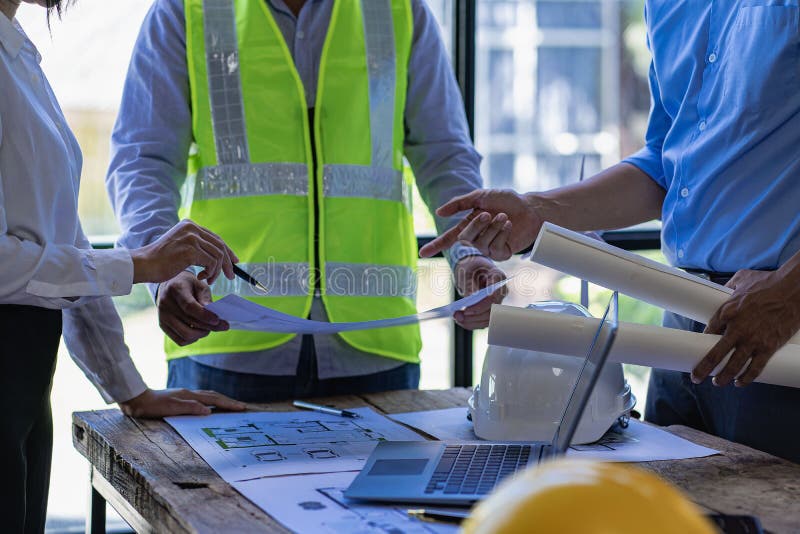 Engineer Pointing at Blueprint and Using Laptop To Draw Building Design ...